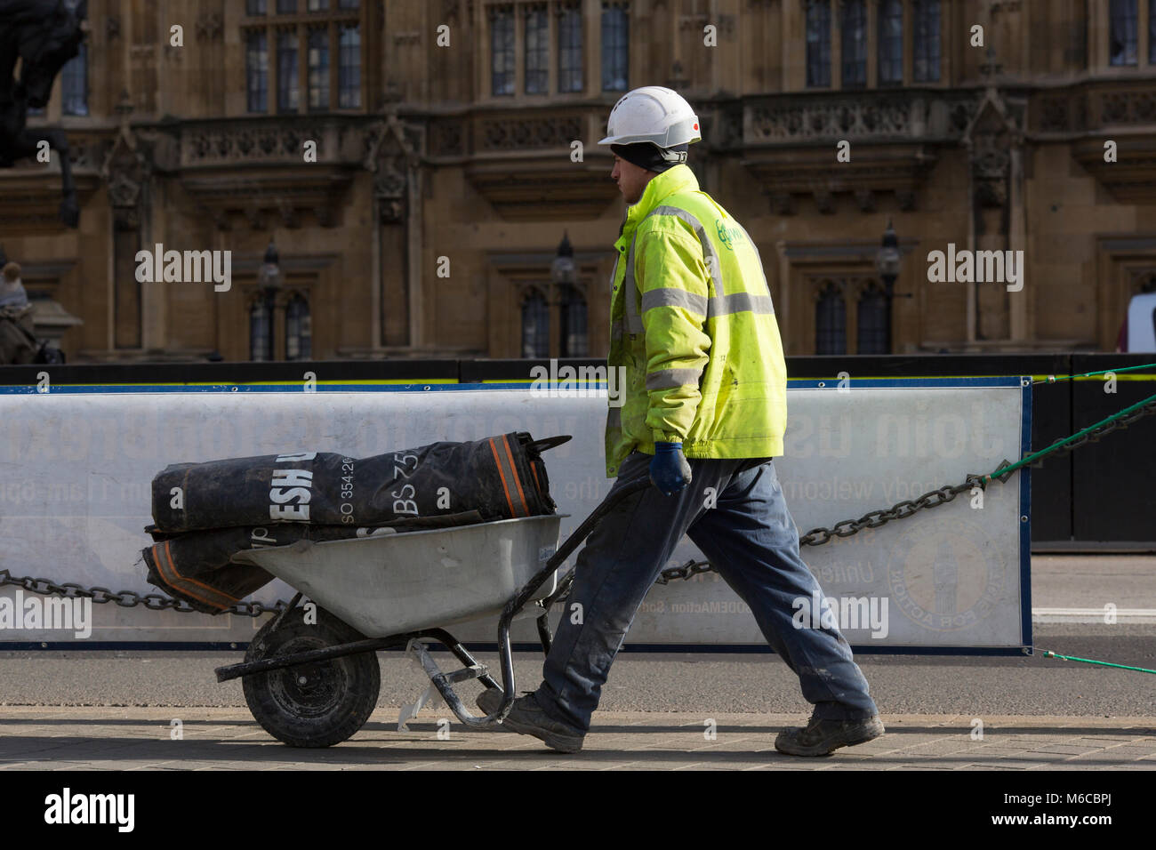 A construction worker wheels materials towards renovated parts of the ...