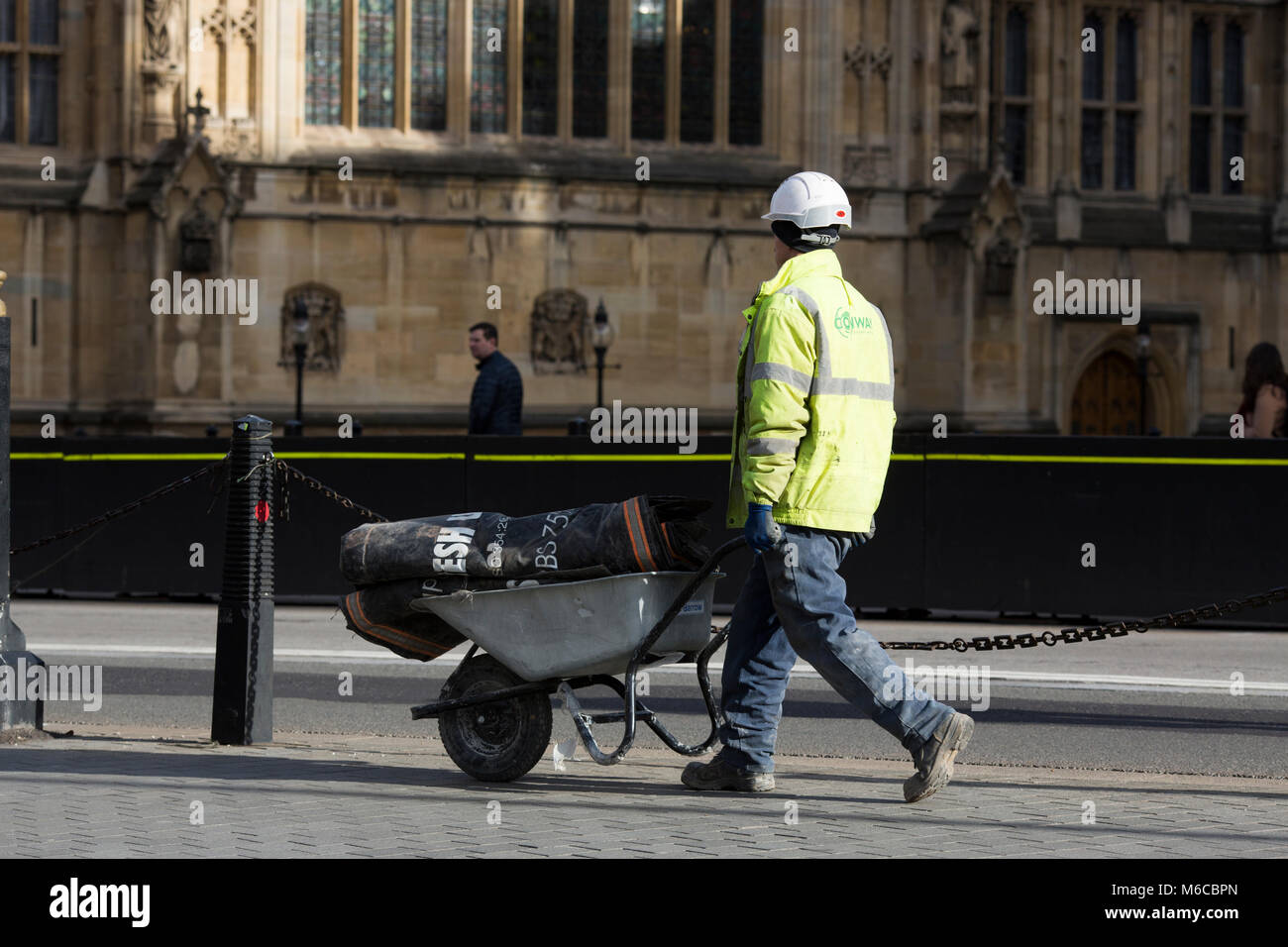 A construction worker wheels materials towards renovated parts of the ...