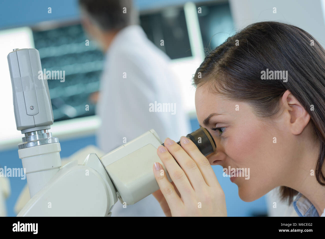 Woman looking into microscope Stock Photo - Alamy