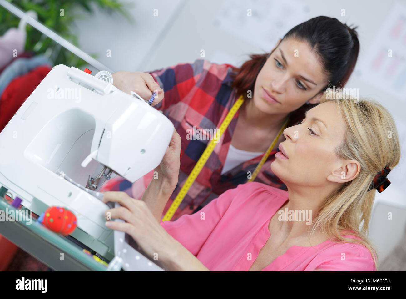 Two women around sewing machine Stock Photo - Alamy