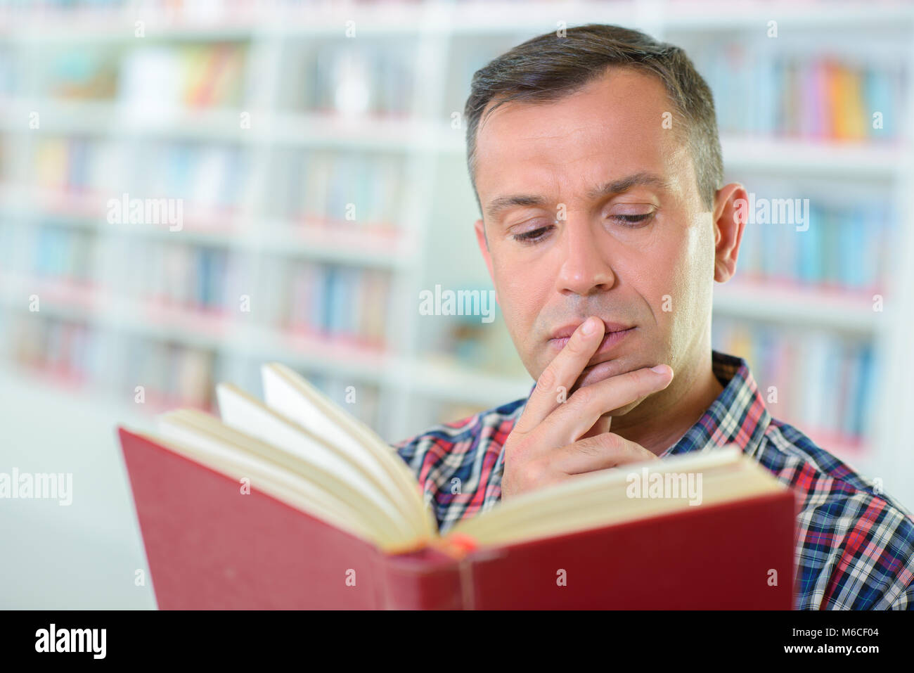 man reading book in library Stock Photo - Alamy