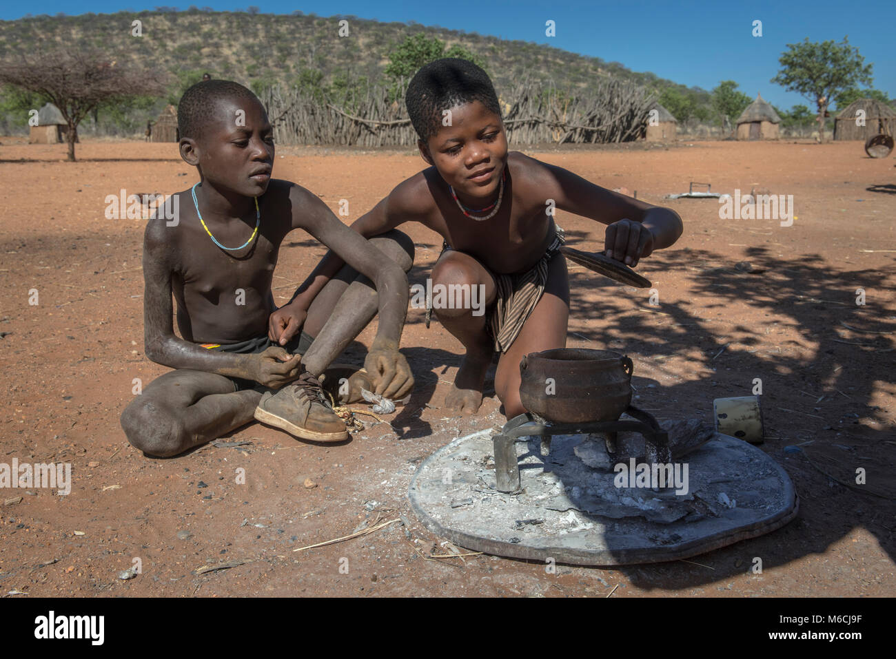 Children of the Ovahimba or Himba people look curiously into a pot over ...