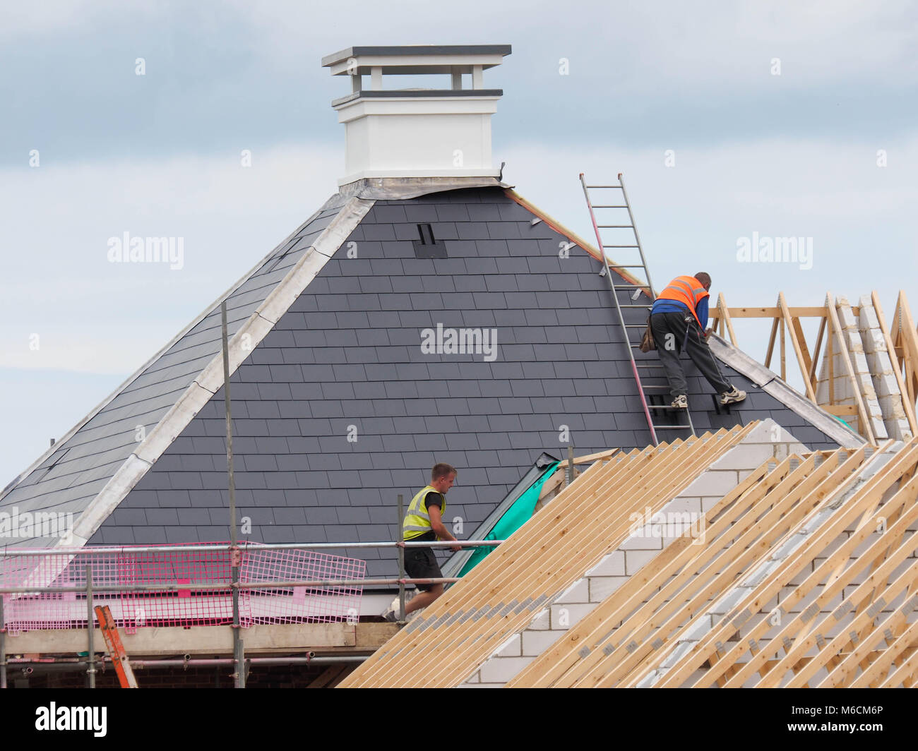 ROOF TILER WORKING ON A BUILDING SITE, NEW BUILD UNDER CONSTRUCTION FOR ...
