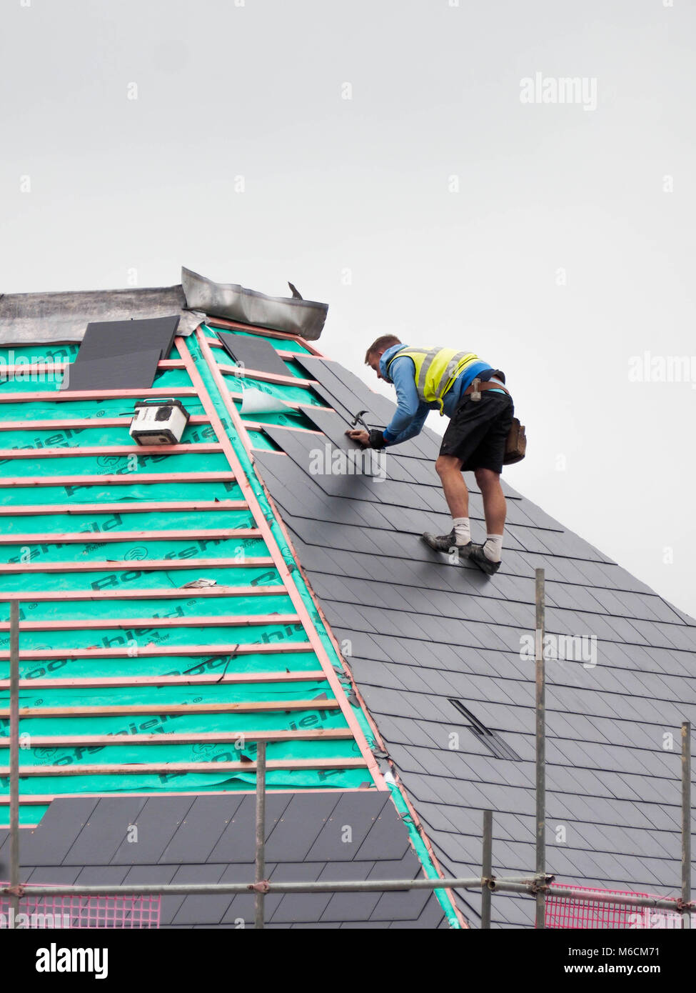 ROOF TILER WORKING ON A BUILDING SITE, NEW BUILD UNDER CONSTRUCTION FOR ...