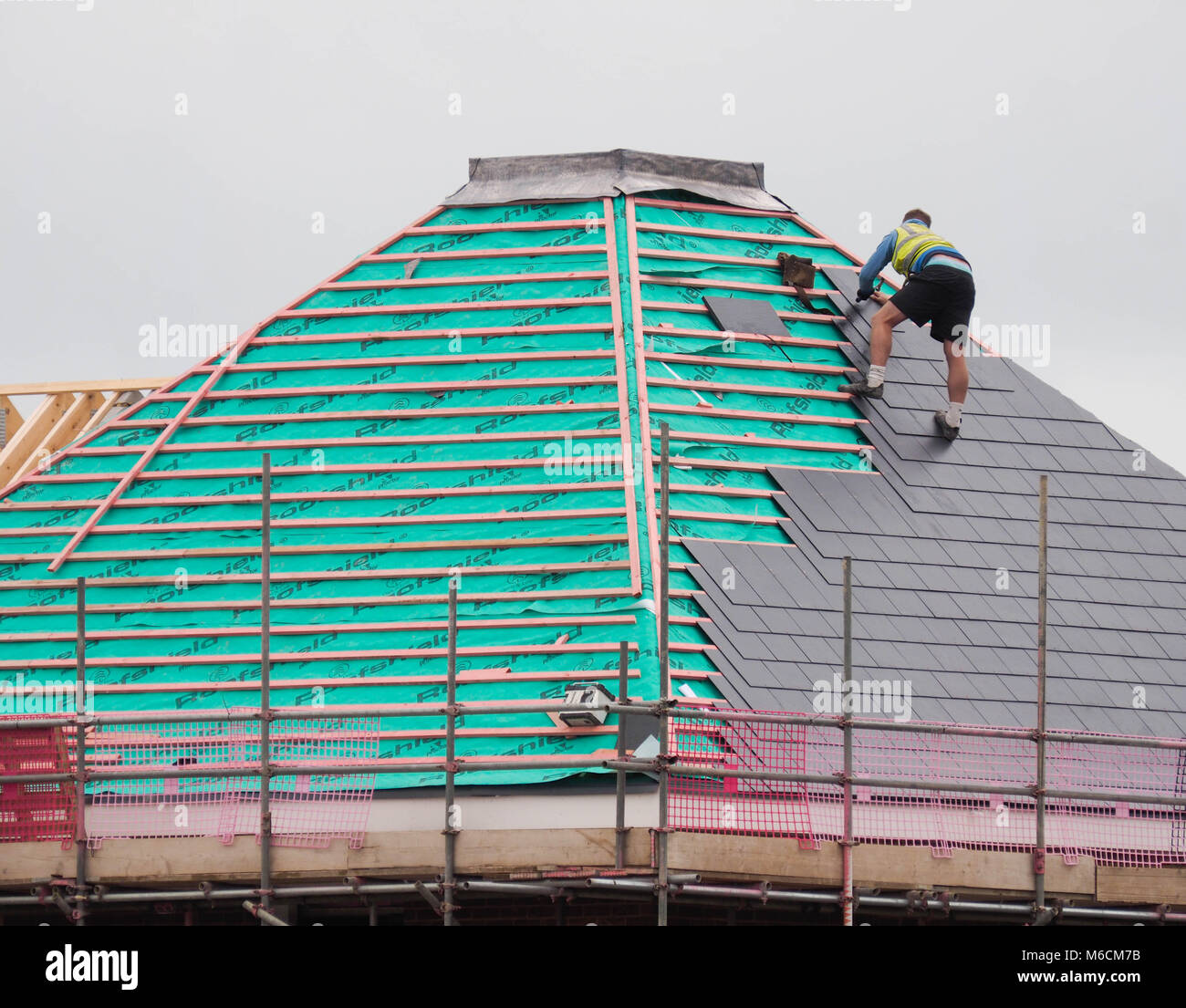ROOF TILER WORKING ON A BUILDING SITE, NEW BUILD UNDER CONSTRUCTION FOR ...