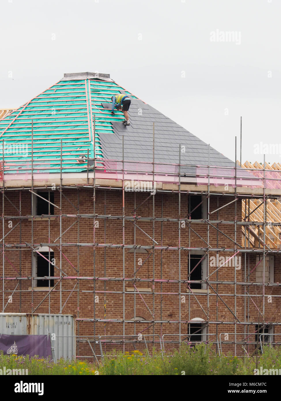 ROOF TILER WORKING ON A BUILDING SITE, NEW BUILD UNDER CONSTRUCTION FOR ...