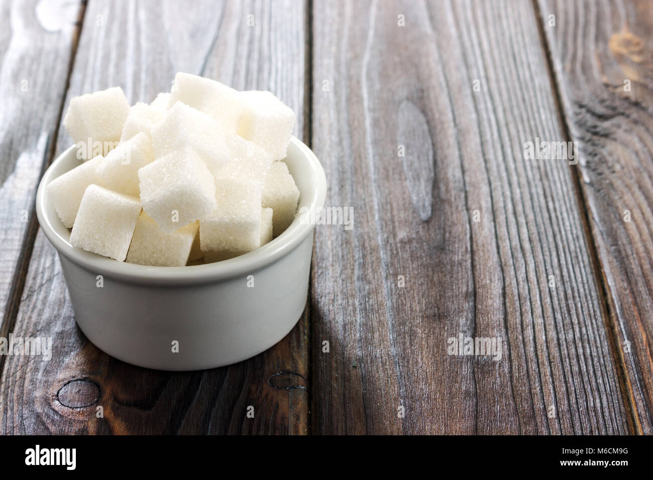 Sugar cubes in ceramic bowl on wooden table Stock Photo - Alamy