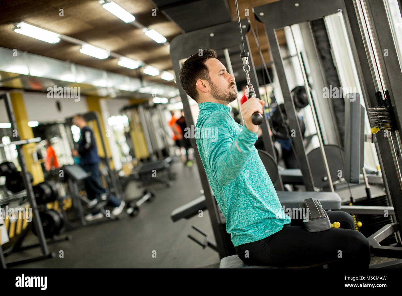 Handsome man doing excersise on a lat machine in gym Stock Photo - Alamy