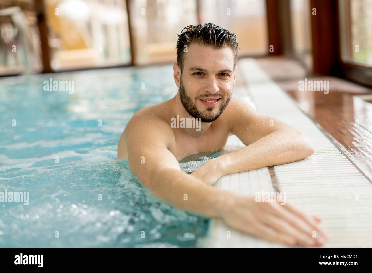 Handsome young man relaxing in the pool at spa Stock Photo - Alamy