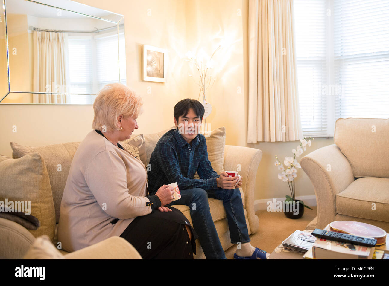 a young asian international student relaxes with his english host at ...