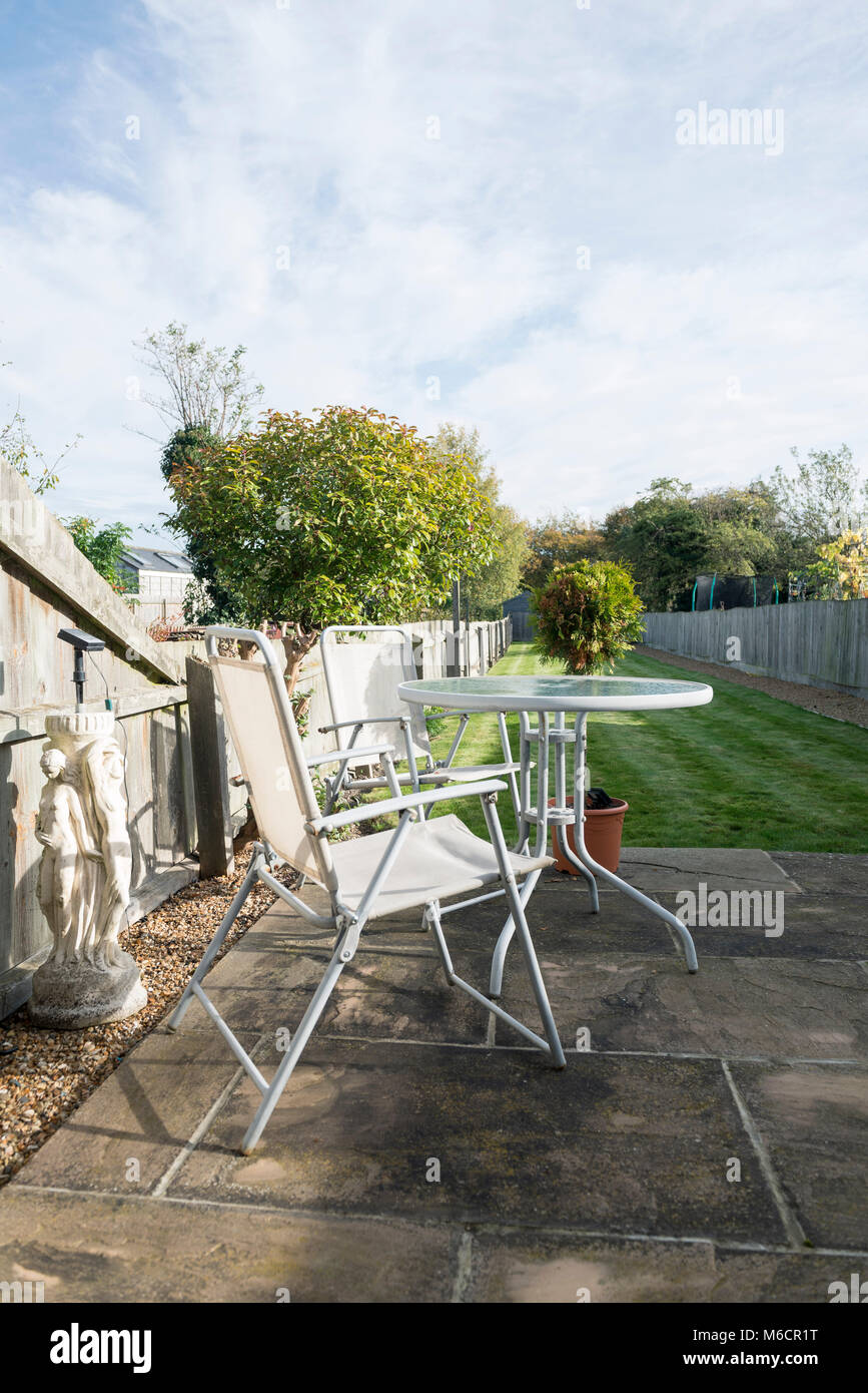 a typically british suburban garden with a patio, lawn, table and ...