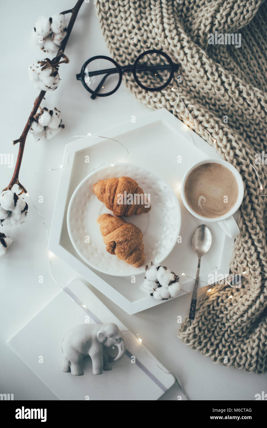 Cozy home breakfast, warm blanket, coffee and croissant on white tray ...