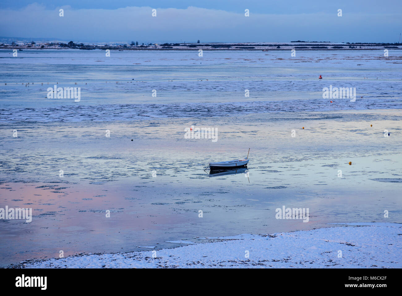 Rowing boat on frozen snow covered foreshore at low tide Thames Estuary ...