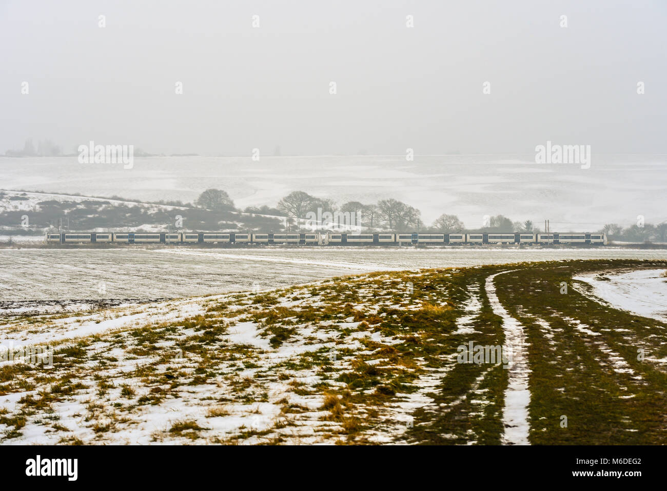 C2C railway train passing through snow covered Hadleigh Country Park ...