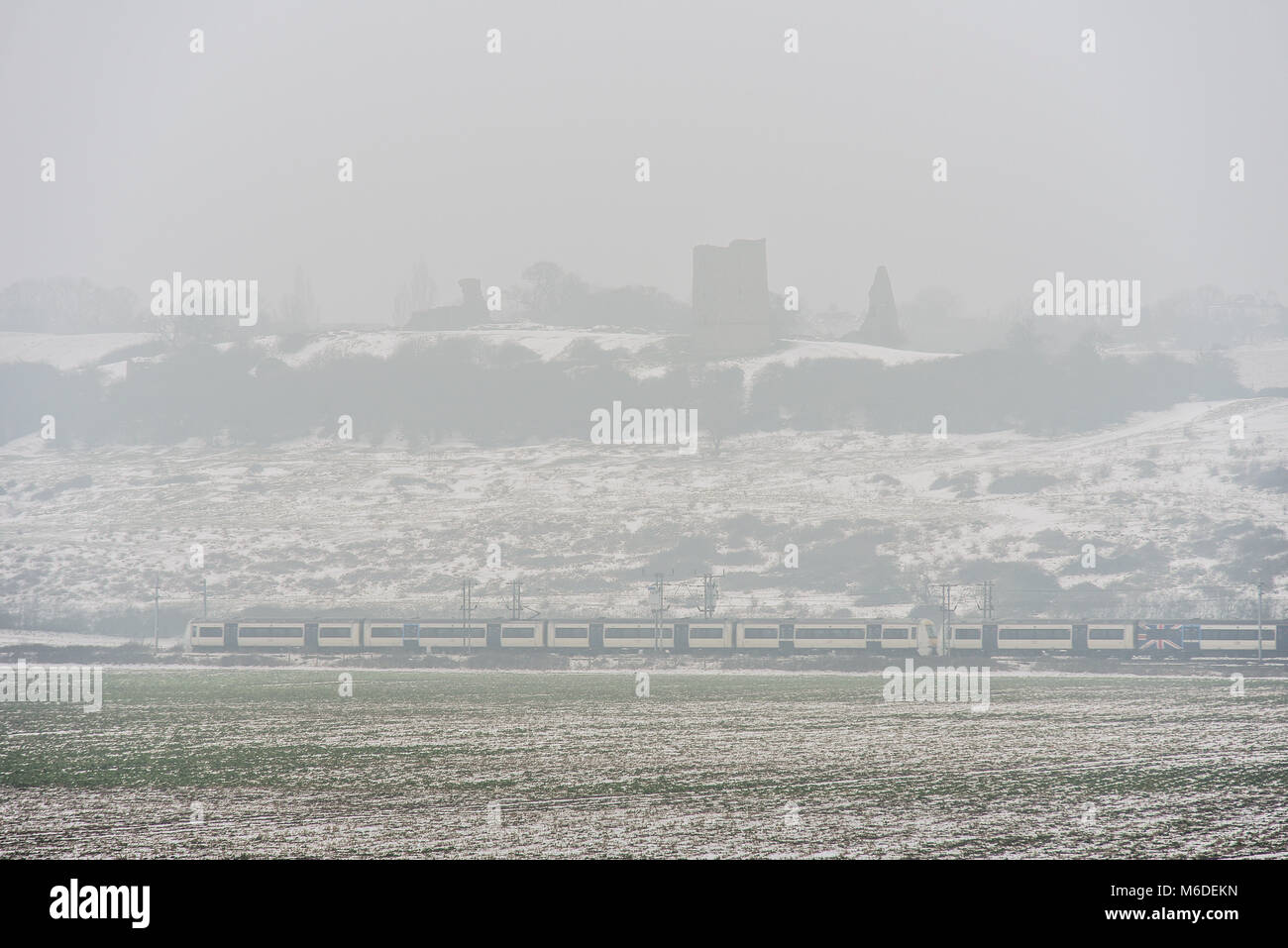 C2C railway train passing through snow covered Hadleigh Country Park ...