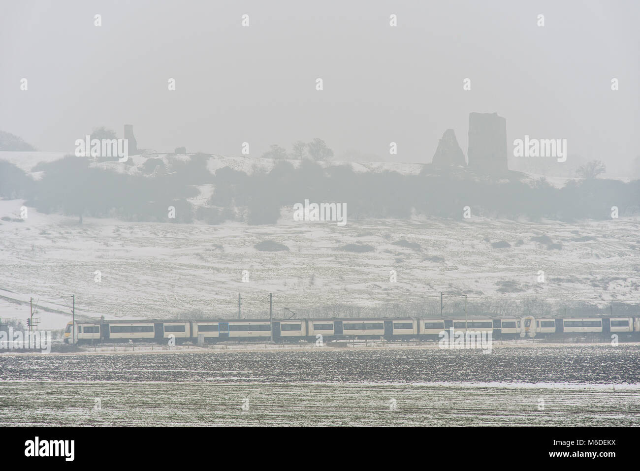 C2C railway train passing through snow covered Hadleigh Country Park ...