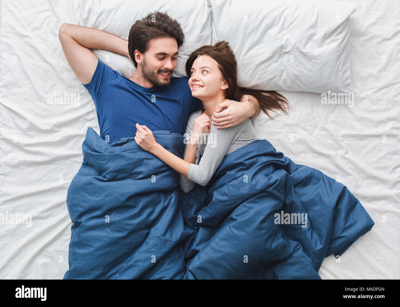 Young couple in bed top view morning concept looking at each other ...