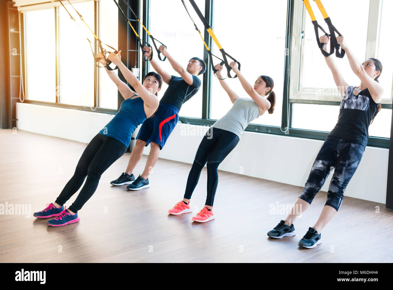 team of Asian people training with TRX total body resistance exercises ...