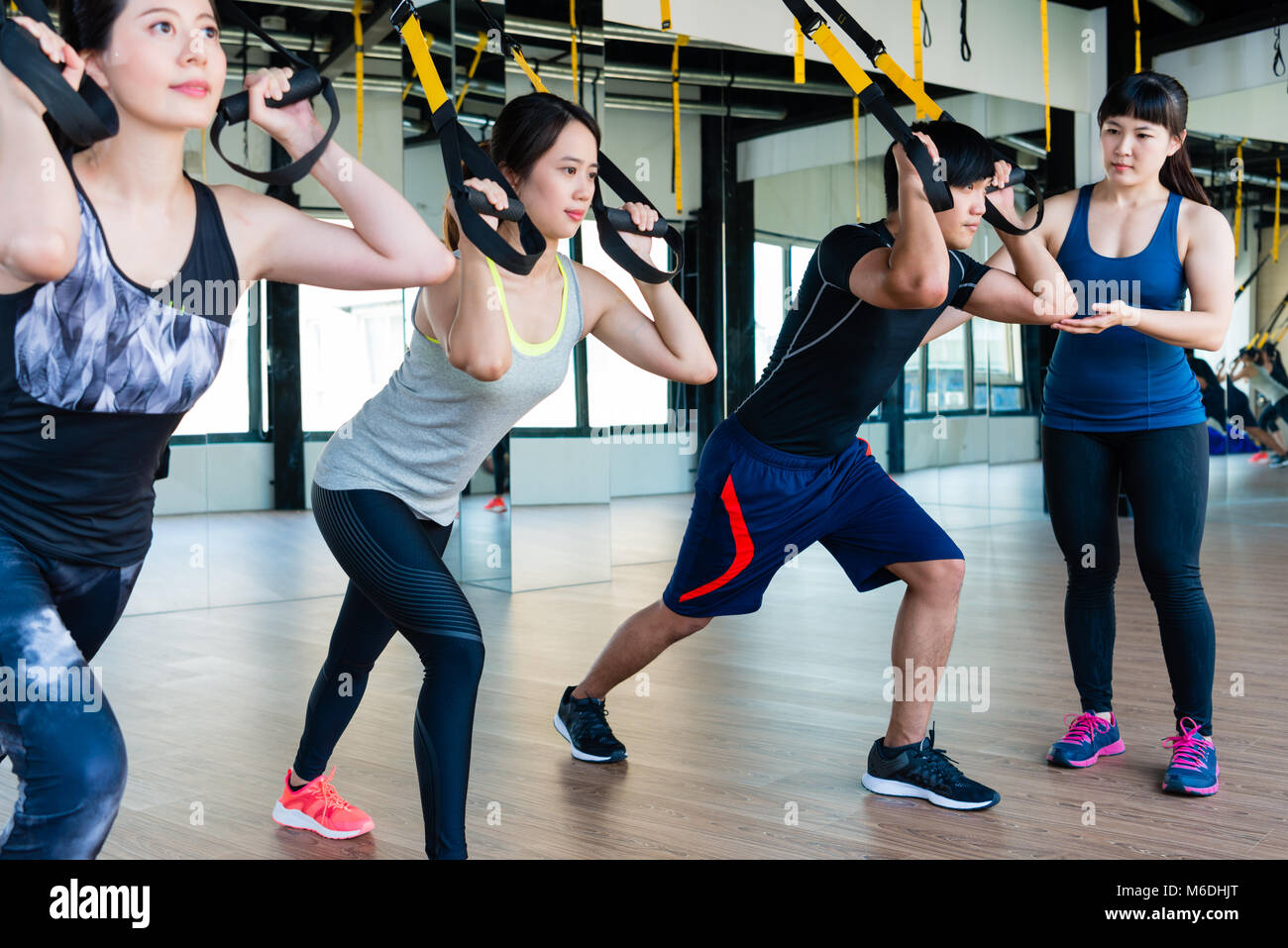 Group of people training in suspension elastic rope at the gym with the ...