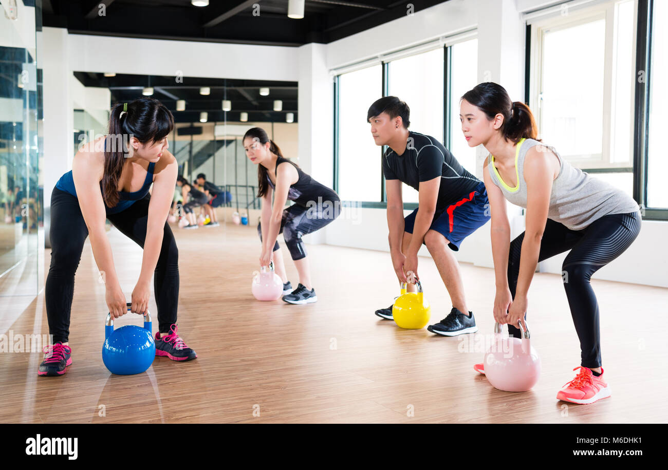 professional Asian fitness trainer teaching how to do kettlebell with ...
