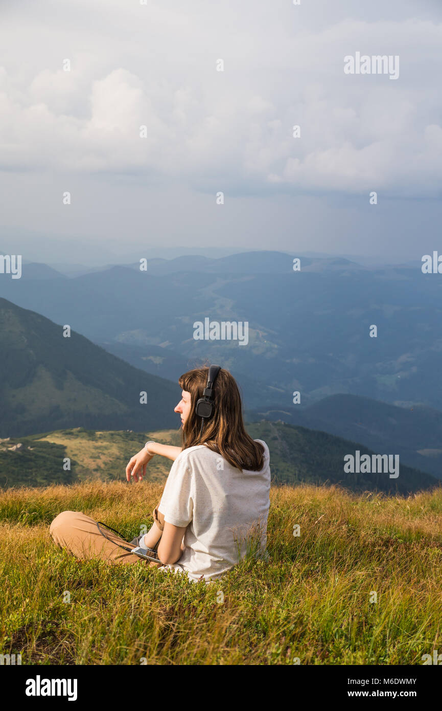 female hiker in headset with cell phone on a mountain meadow of ...