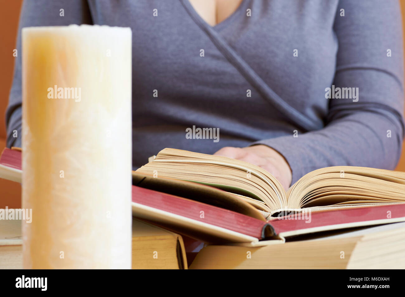 sitting woman reading a book with a standing candle Stock Photo - Alamy