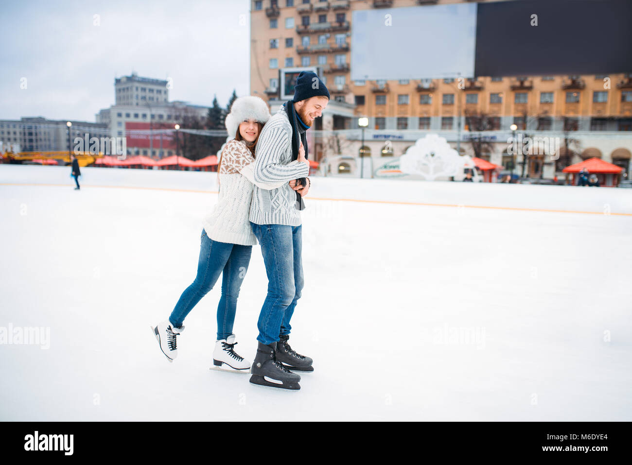 Happy love couple poses on skating rink. Winter ice-skating on open air ...
