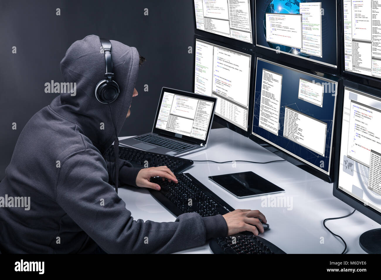 Rear View Of A Hacker Using Multiple Computers For Stealing Data In 7772