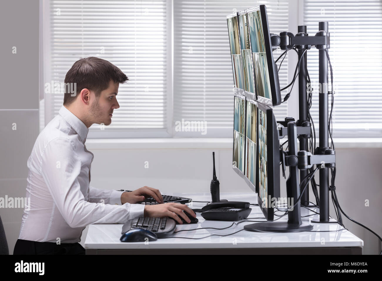 Side View Of A Young Male Operator Looking At Multiple Camera Footage ...