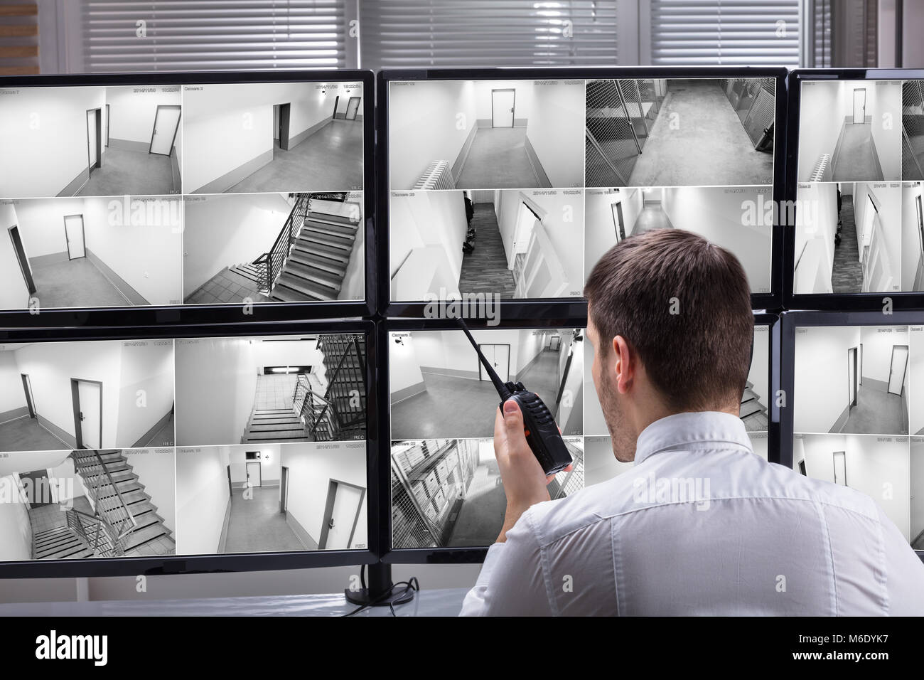 Young Male Security Guard Talking On Walkie-talkie While Monitoring ...