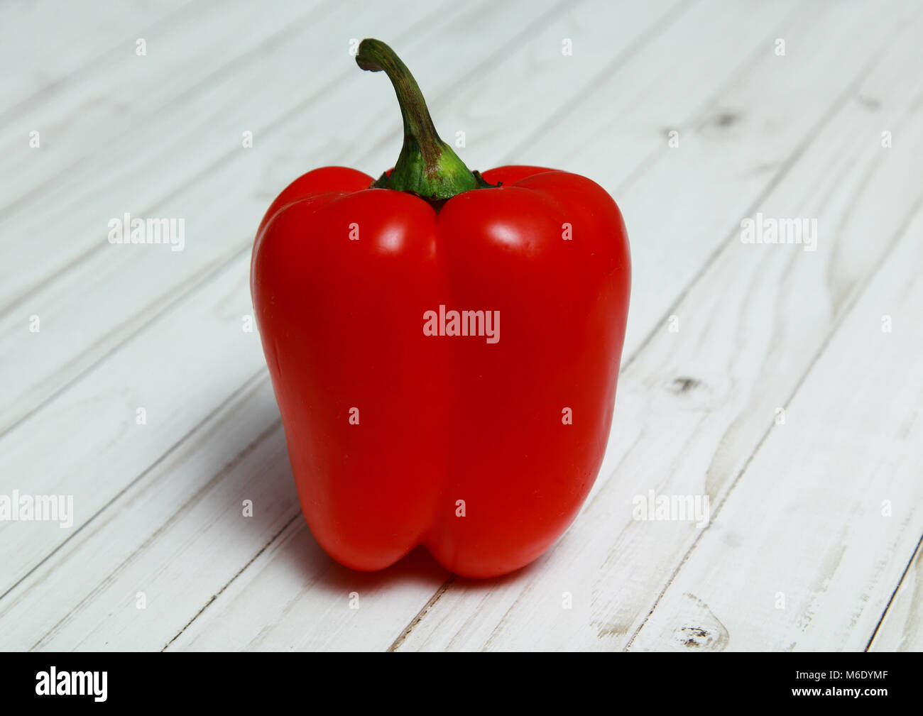 Large red bell pepper in the center of a white wooden table Stock Photo ...