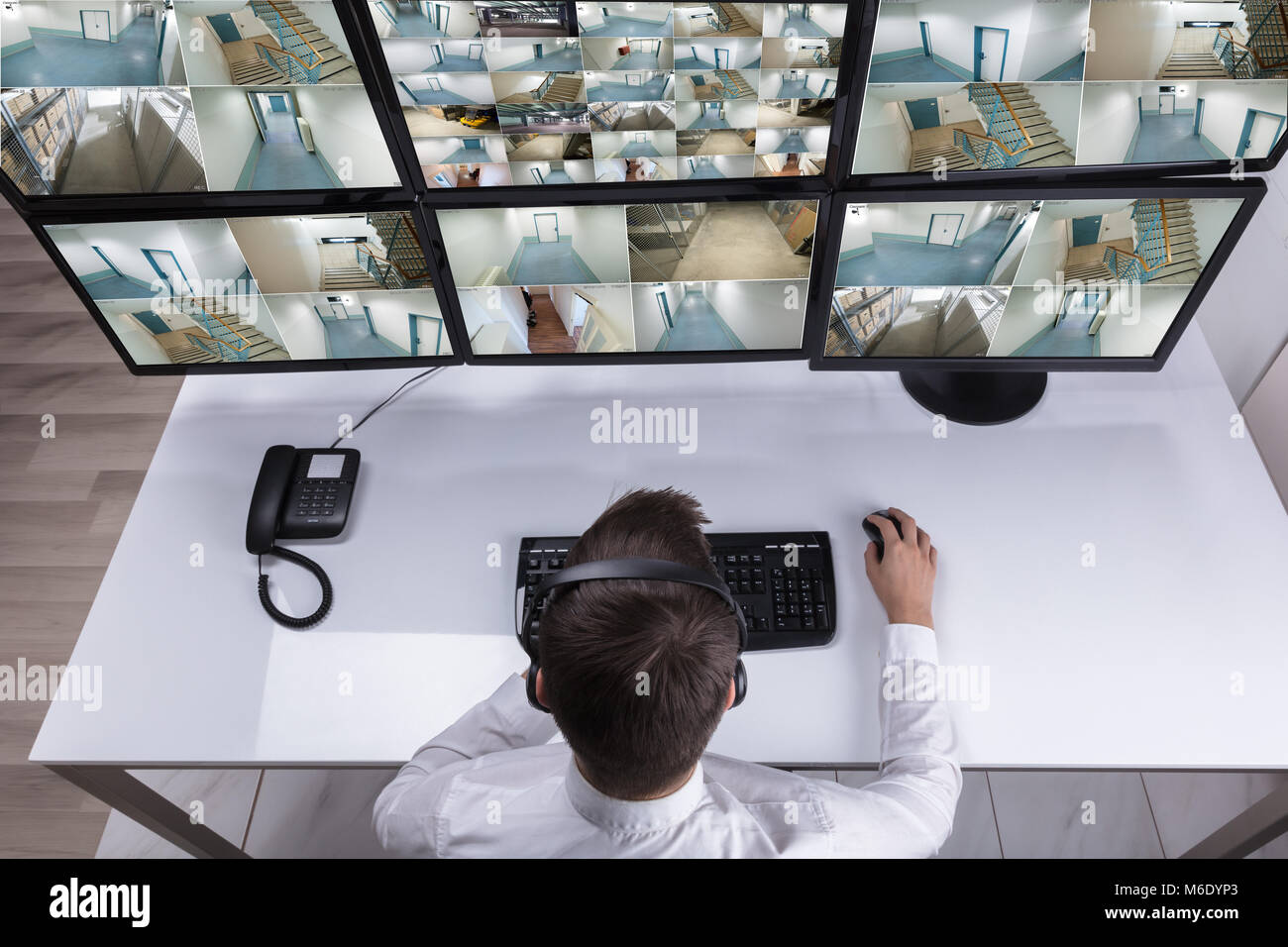 Elevated View Of Male Security Guard Monitoring Multiple Camera Footage ...