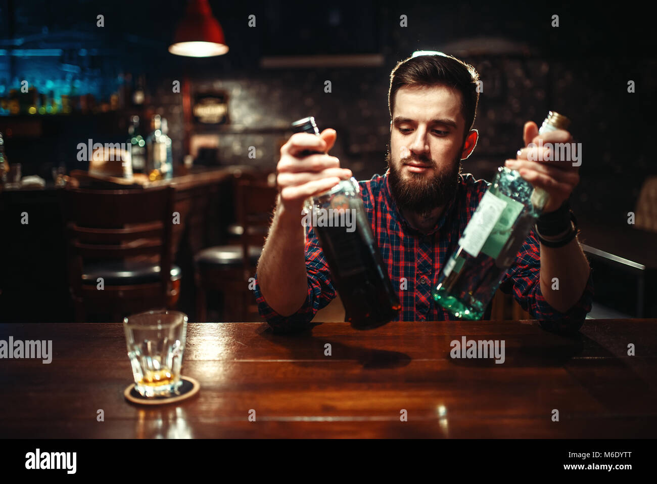 Alcoholic sitting at the bar counter with two bottles of alcohol ...