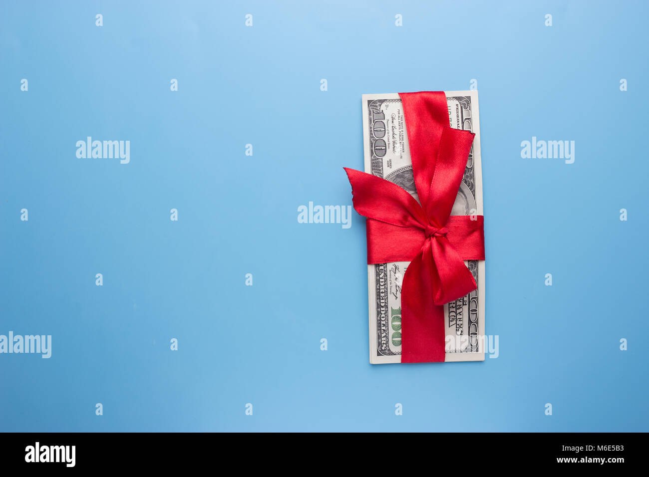 Red Ribbon on Bunch of US dollars on blue background Stock Photo - Alamy