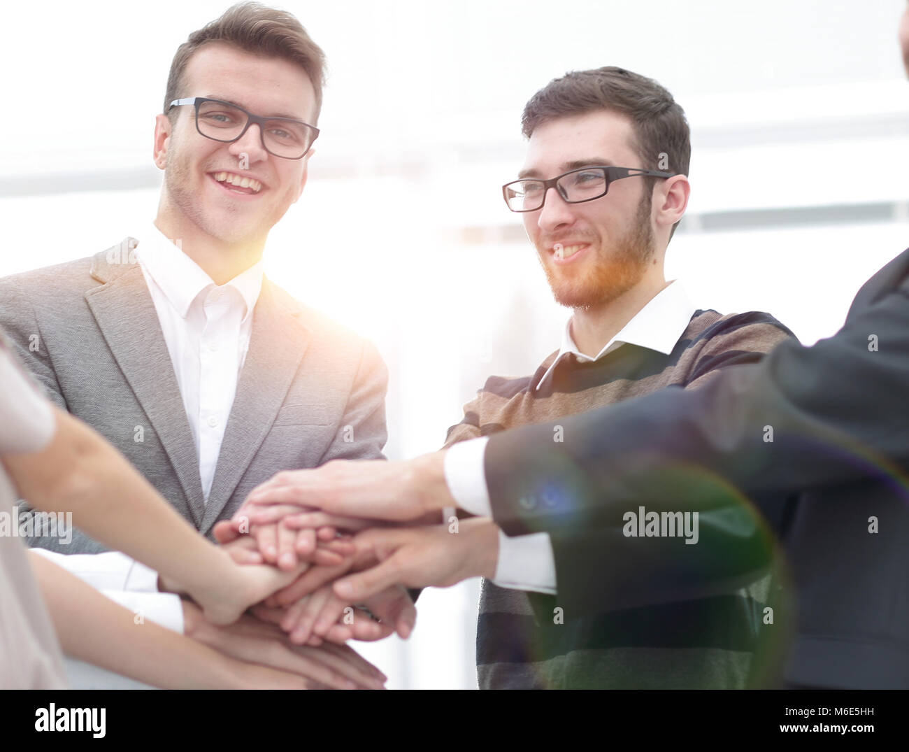 Business team standing joining hands together Stock Photo - Alamy