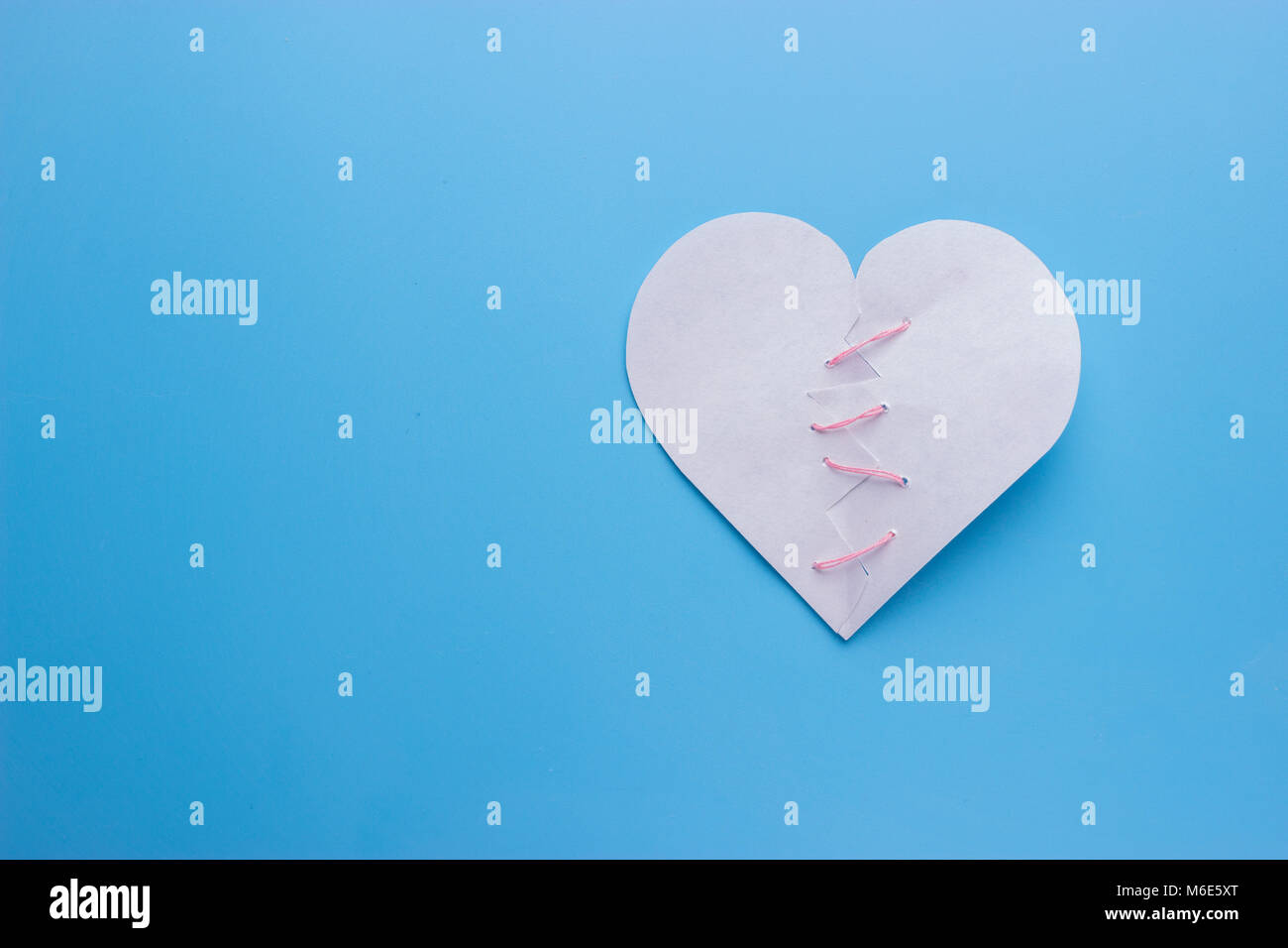 Healing broken heart. needle with pink thread Stock Photo - Alamy