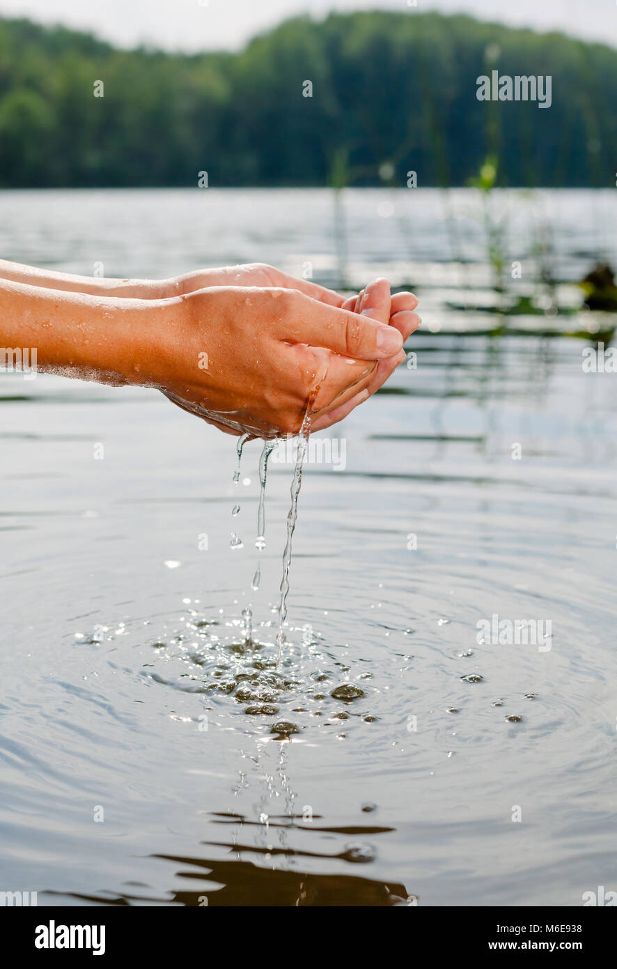 Woman taking raw unfiltered water from a natural source by cupped hands ...