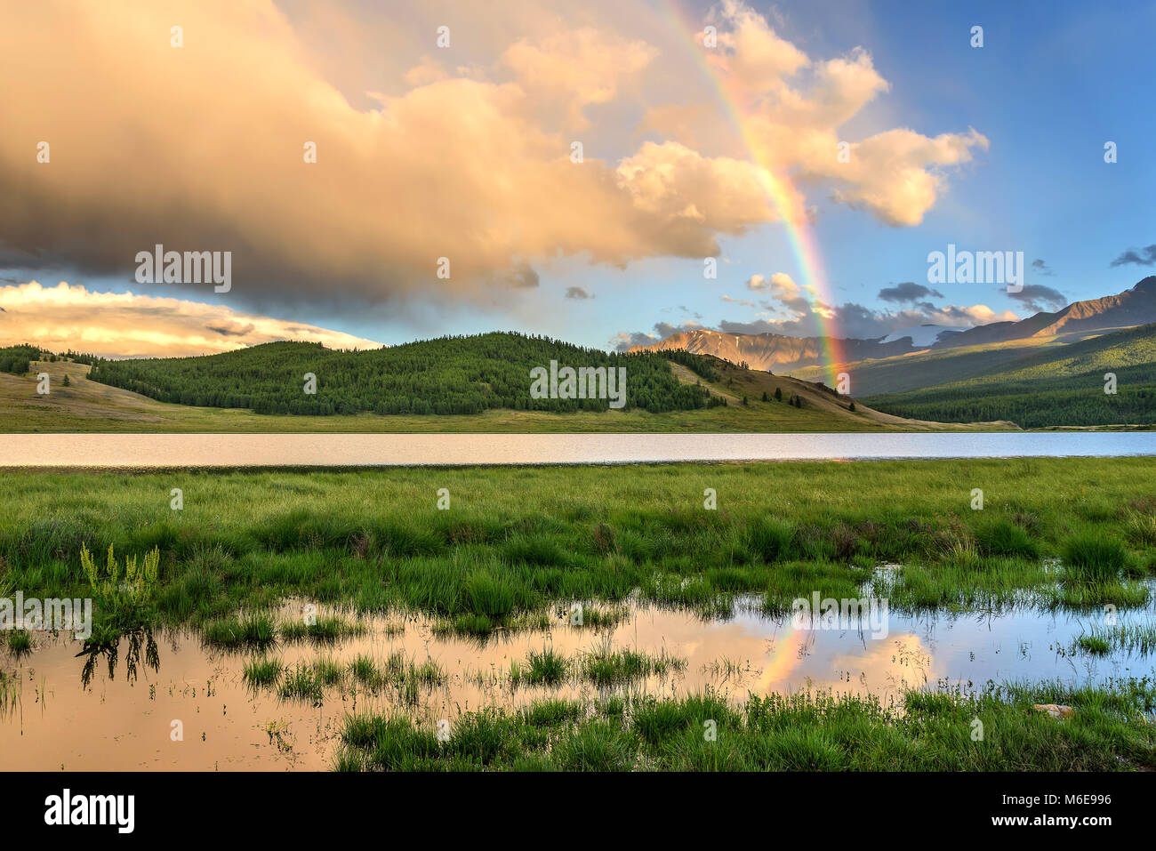 Bright colorful rainbow over the mountains, lake and forest after the ...