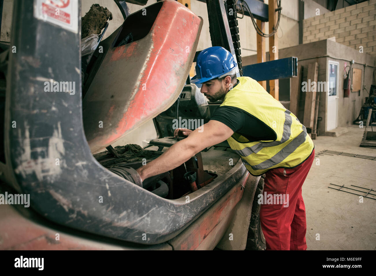 Man repairing forklift in concrete factory Stock Photo - Alamy