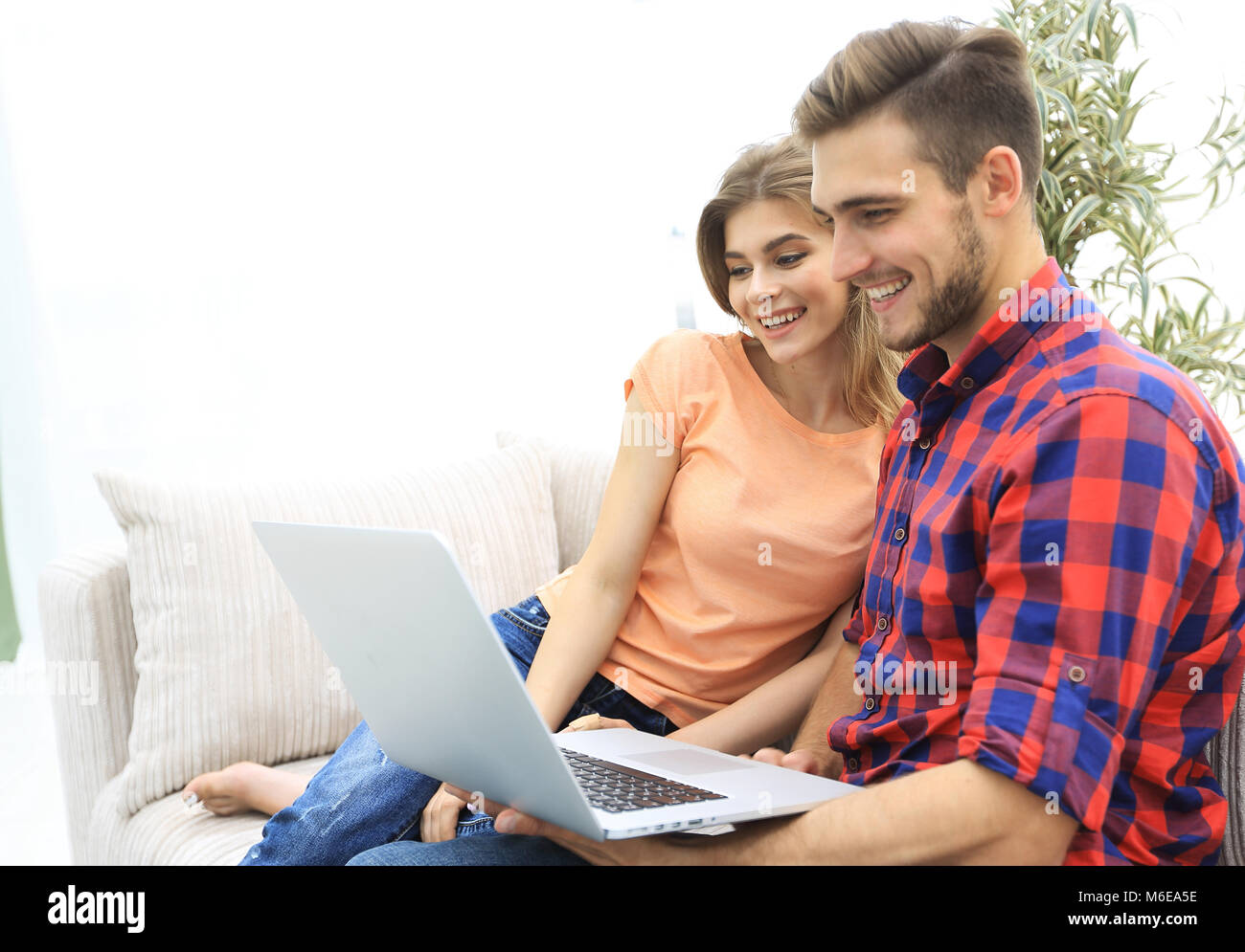 smiling young couple with laptop sitting on the couch Stock Photo - Alamy