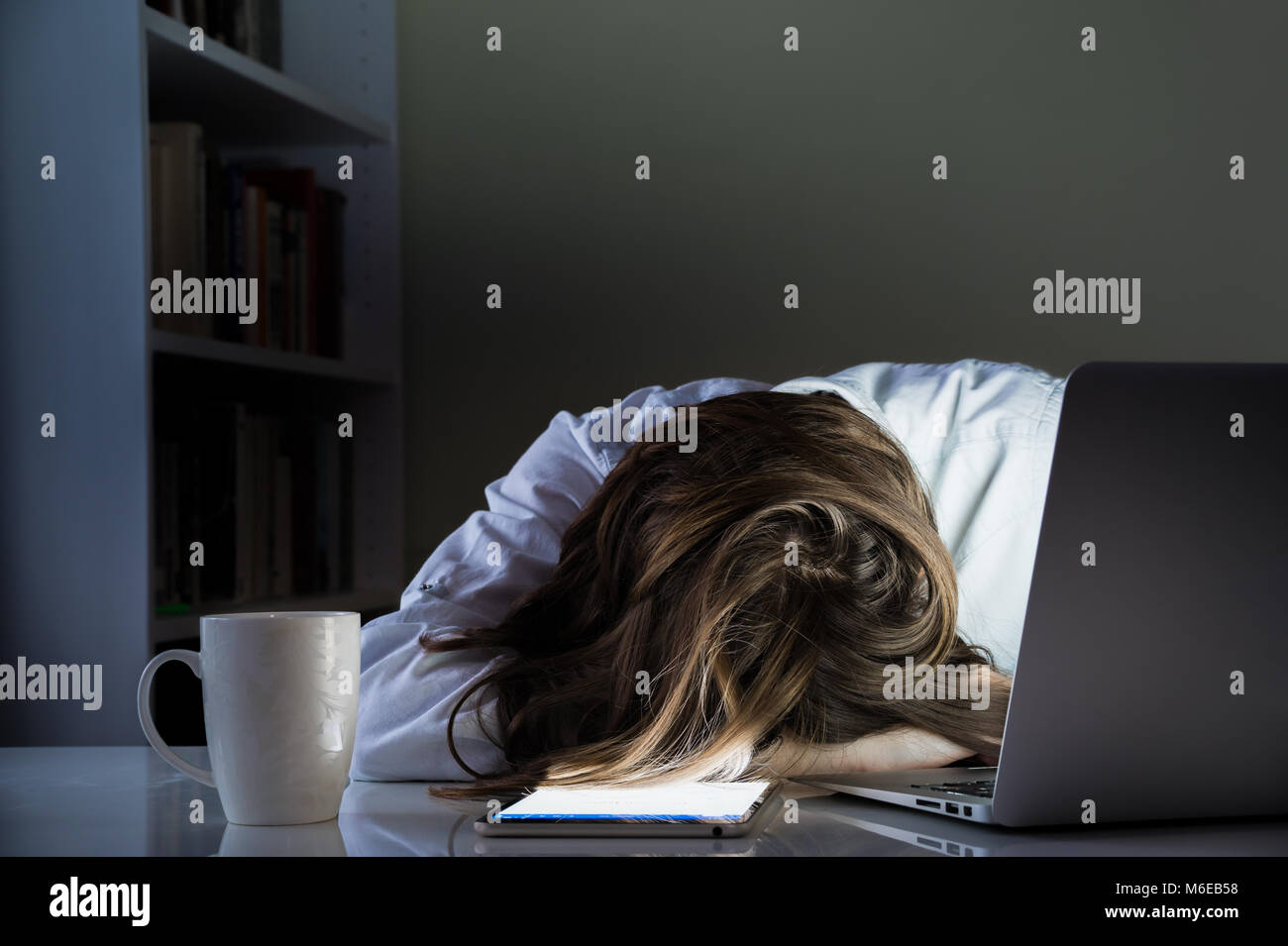 Tired person sleeping at desk in home office with turned on computer ...
