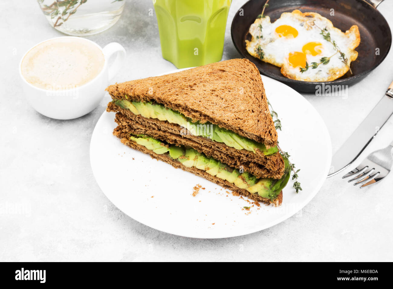 Breakfast - a toast from rye bread with avocado, fried eggs, lemonade ...