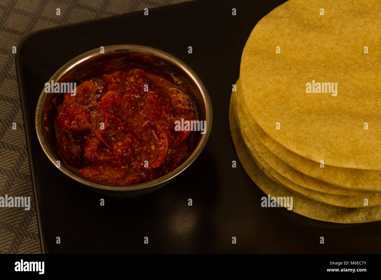 Indian poppadums stacked with bowl of lime pickle and sliced lime Stock ...