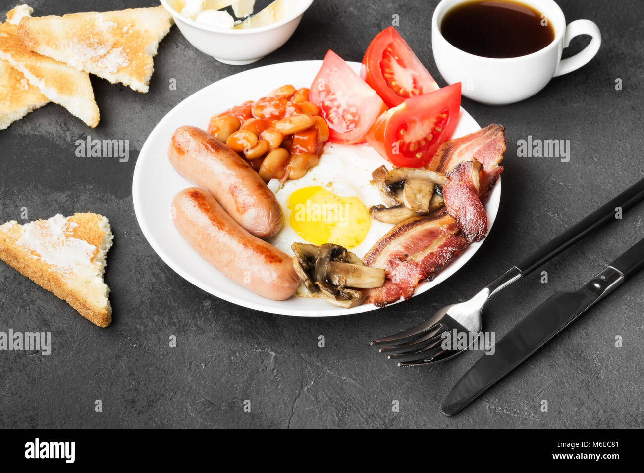 Traditional English breakfast - bacon, sausages, fried eggs, tomatoes ...