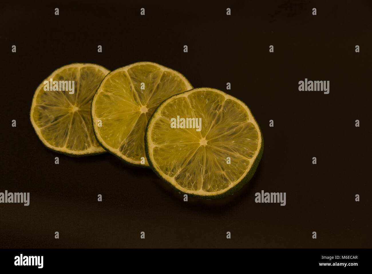 Three slices of lime spread on black background Stock Photo - Alamy