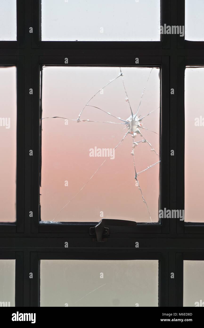 A broken window made of opaque glass in a black wrought iron frame ...