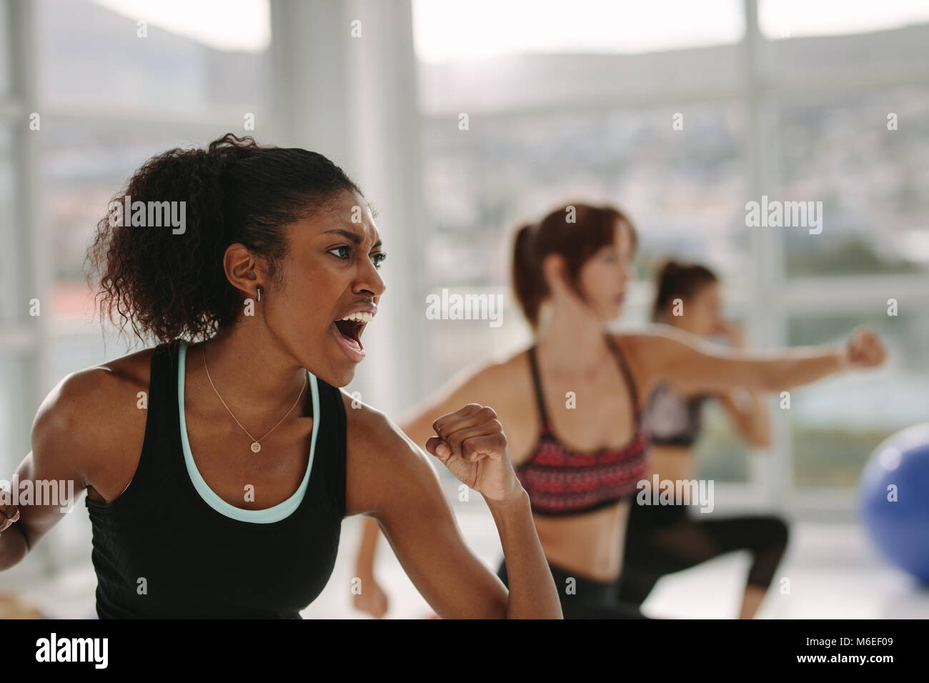 Group of women in gym class doing punching exercise. African woman ...