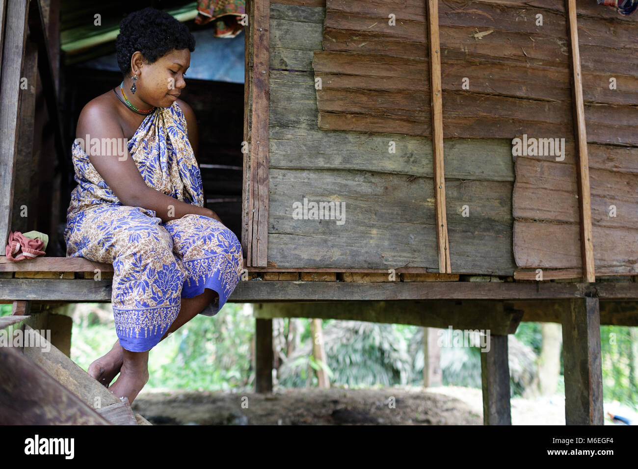Woman from Batek Tribe sitting at the door of traditional house ...