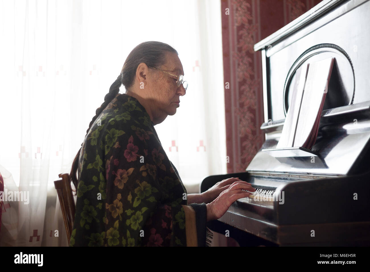 The old lady playing classical music on the rarity piano at home Stock ...