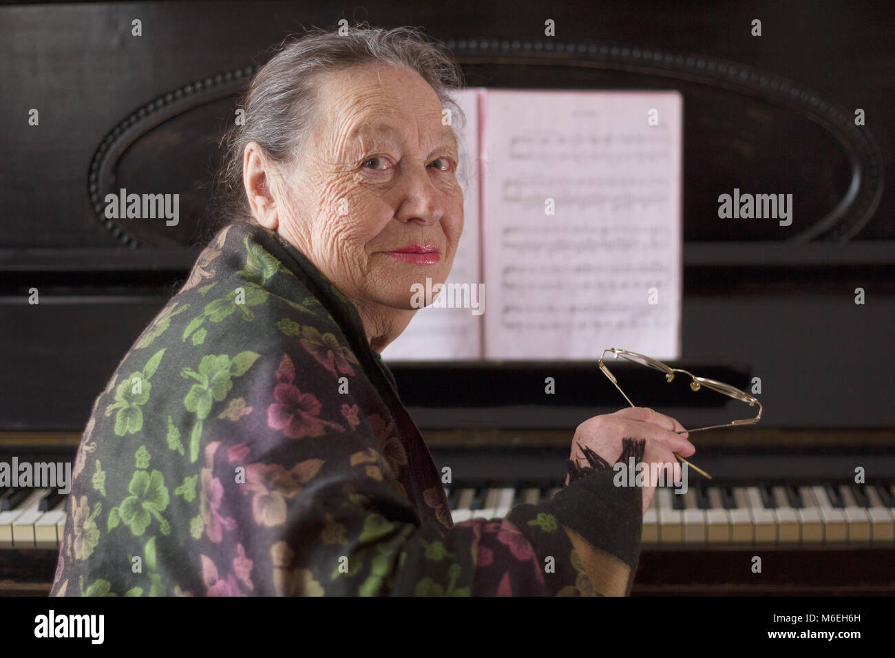 Old smiling lady pianist seating at the piano Stock Photo - Alamy